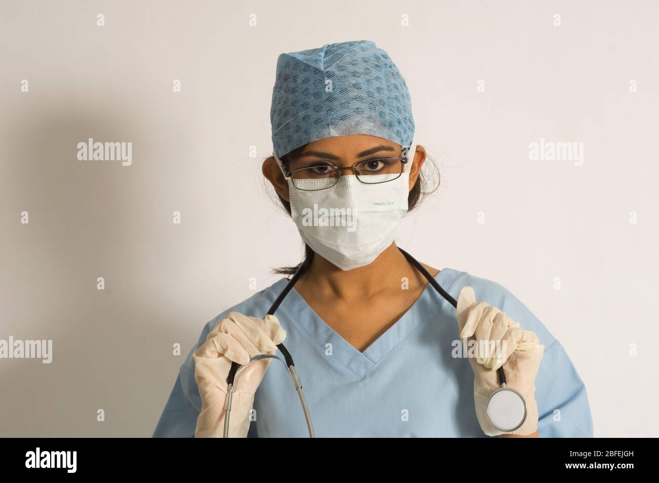 Female surgeon with face mask holding a stethoscope around her neck ...