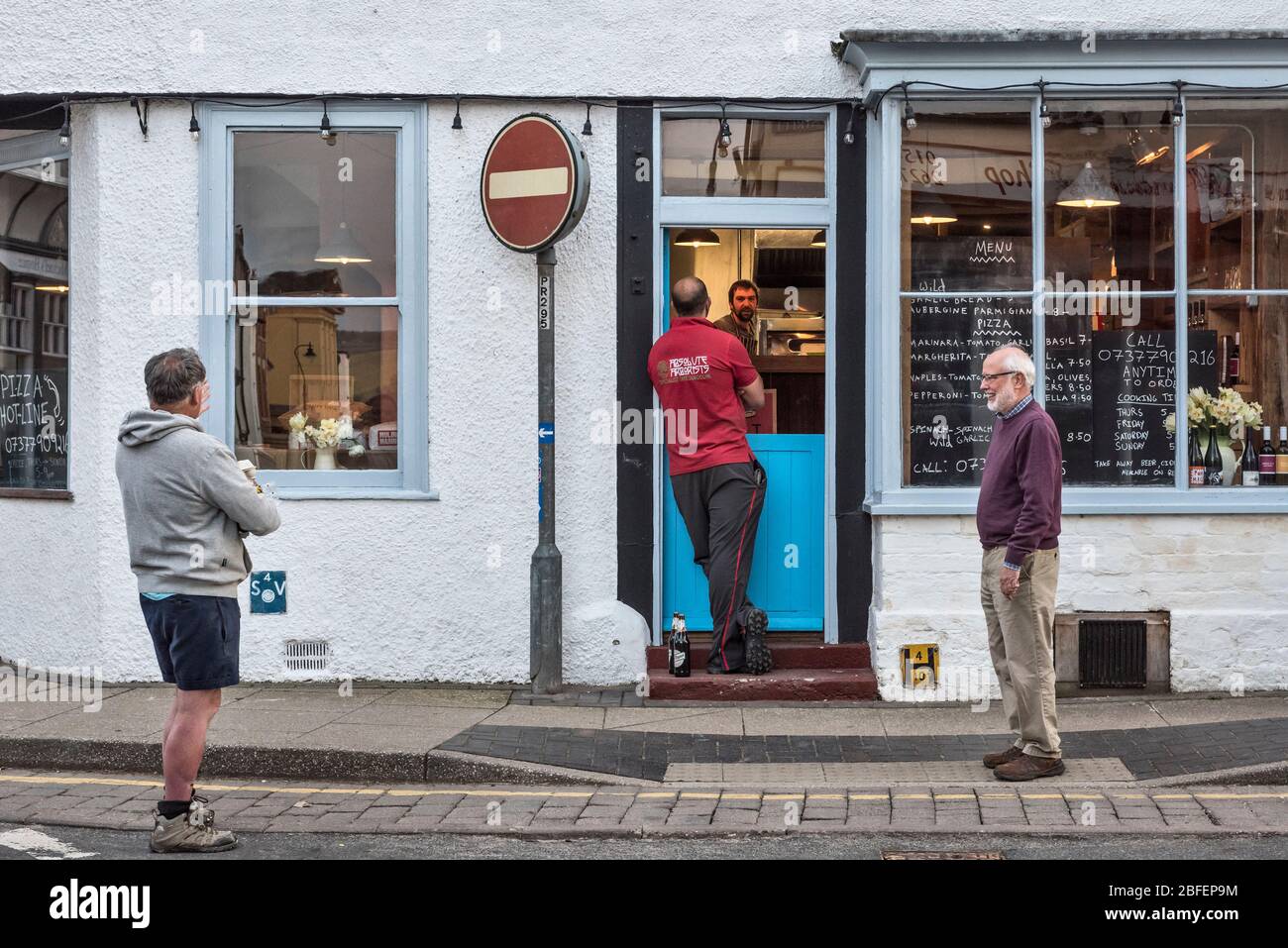 Three customers maintaining social distancing while waiting for a ...