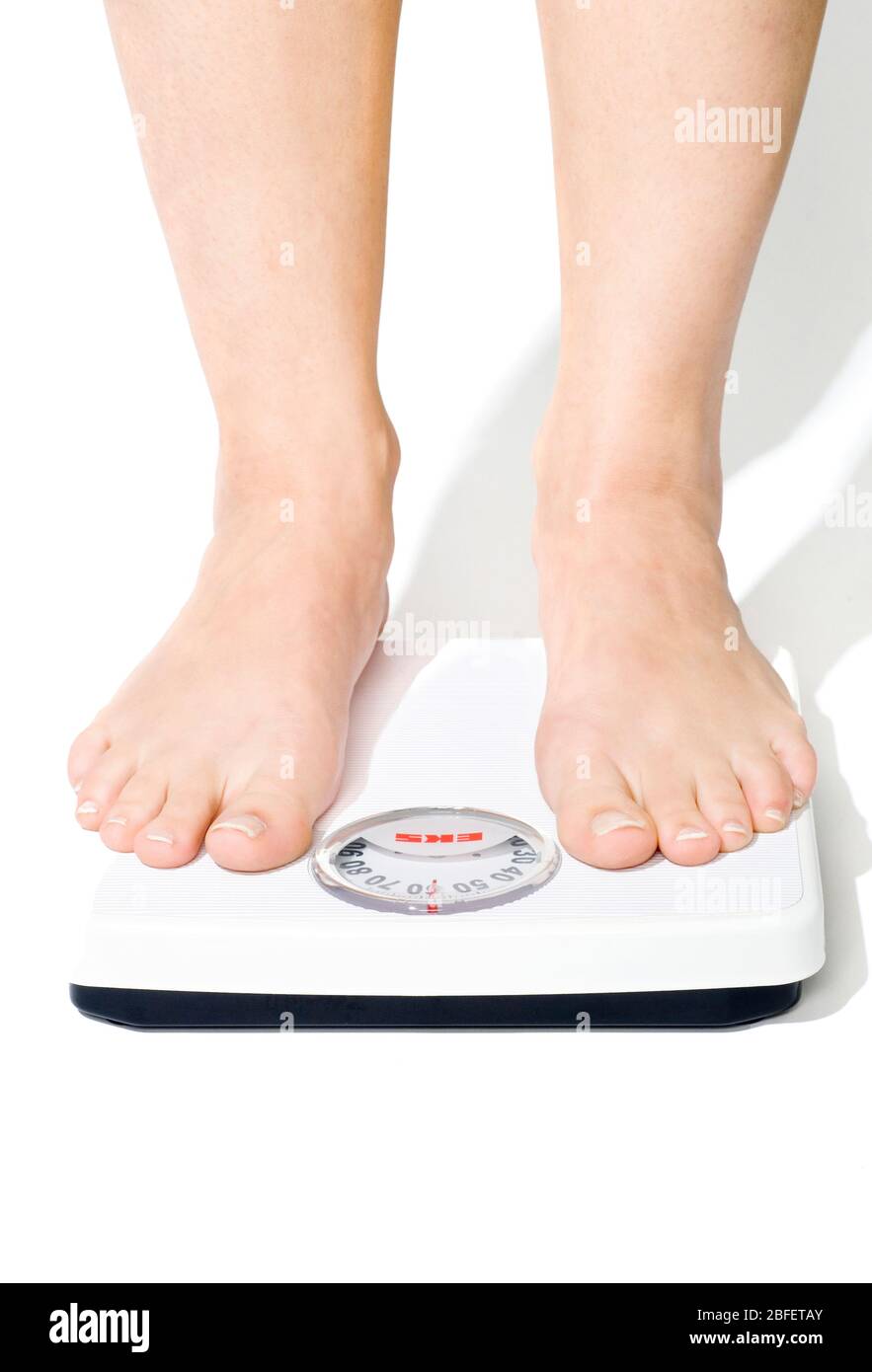 A woman measuring her weight on a set of bathroom scales -Model ...