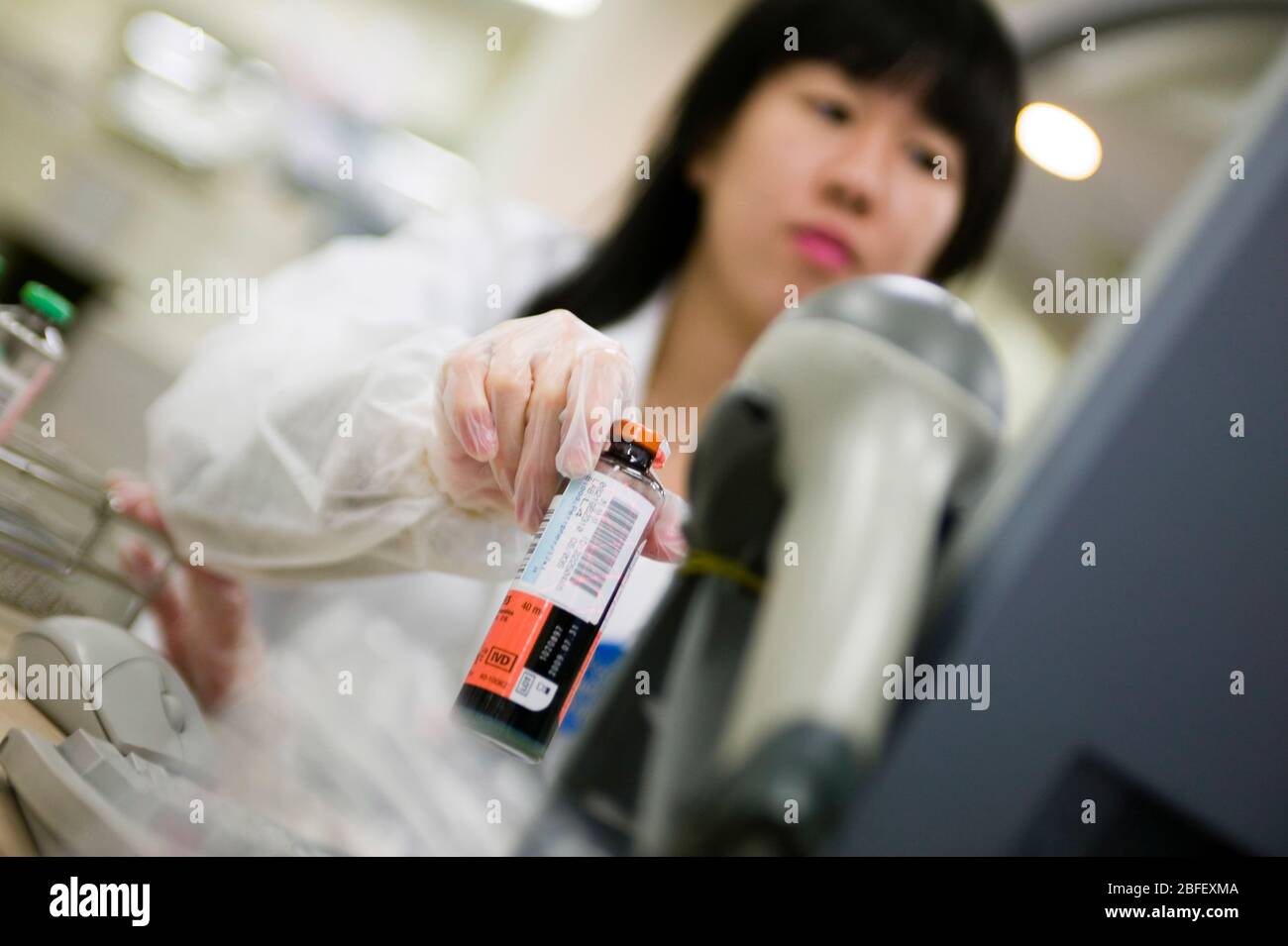A laboratory technician scanning a blood sample into a analysis machine ...
