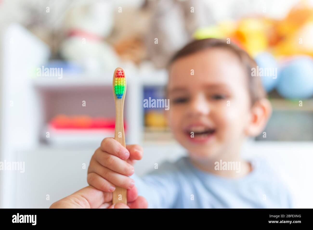 laughing toddler boy taking a rainbow toothbrush from his father hand ...