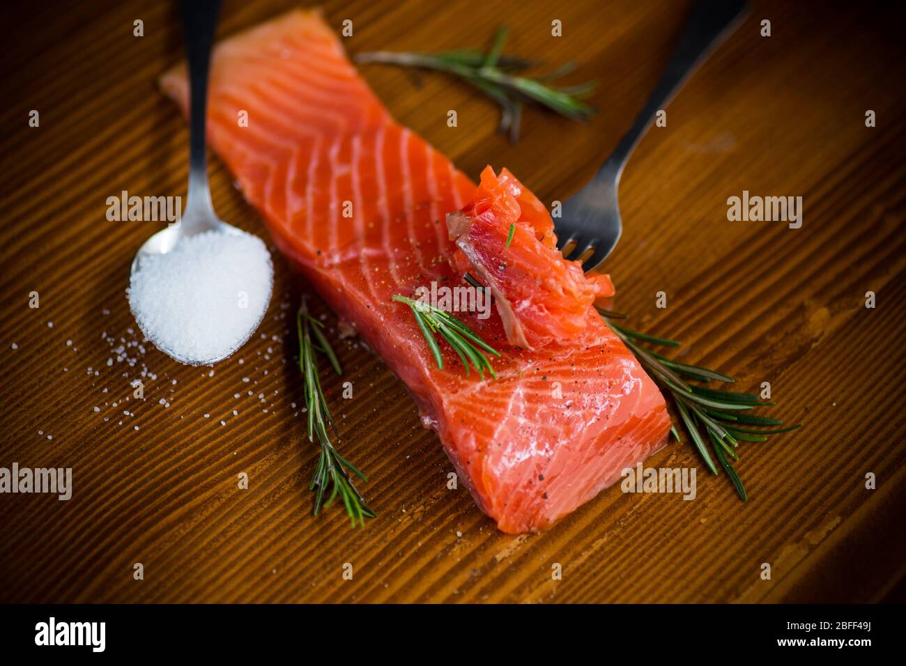 salty red fish on a fork, wooden background Stock Photo - Alamy