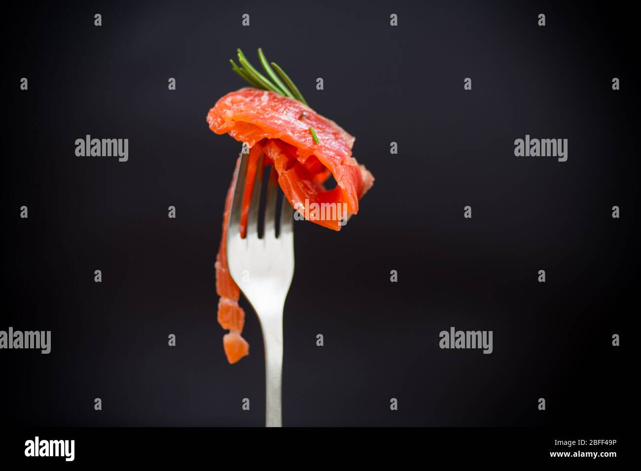 salty red fish on a fork, black background Stock Photo - Alamy