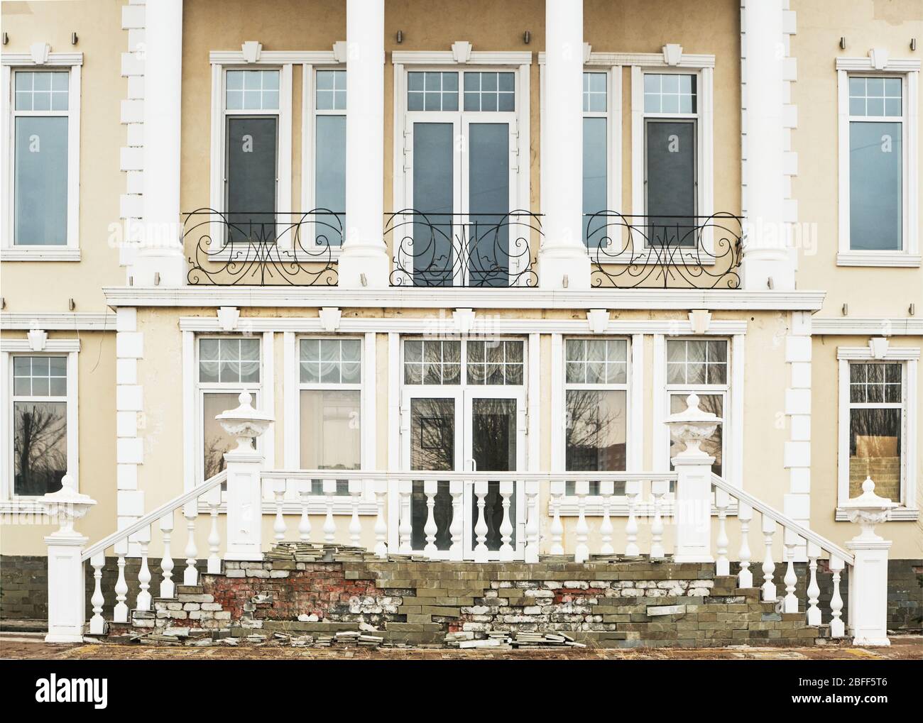 Facade of a crumbling abandoned building with white columns Stock Photo ...