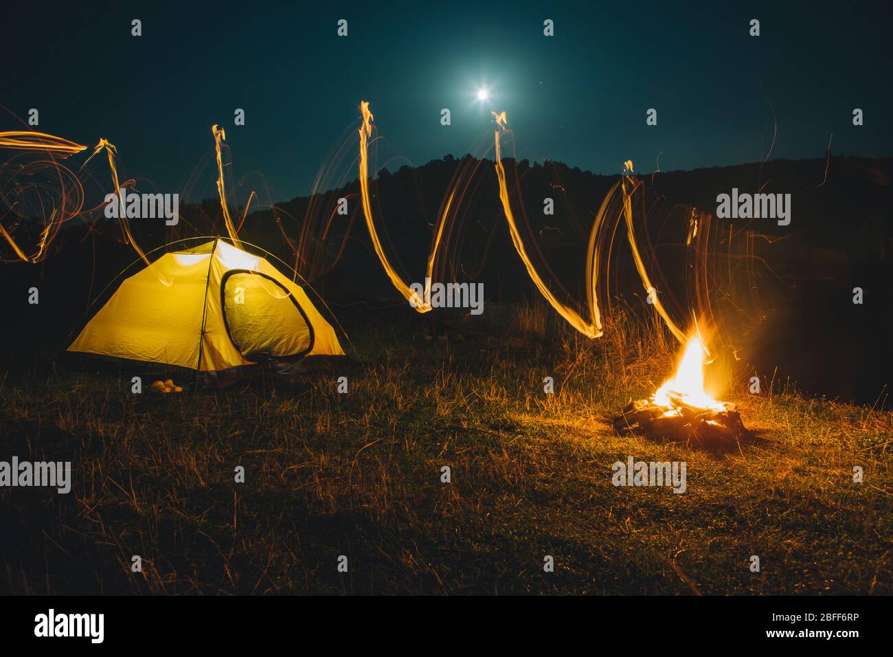 long exposure bonfire with yellow tent on background Stock Photo - Alamy