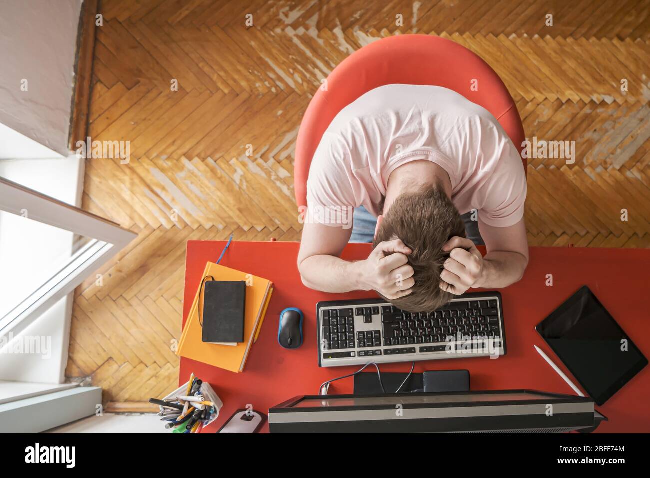 Man works remotely at home on a computer and he experiences stress ...