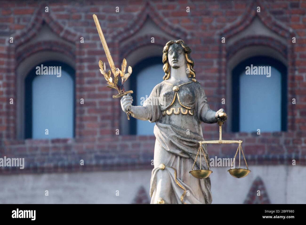 Justitia blindfolded and holding balance scales and a sword on ...