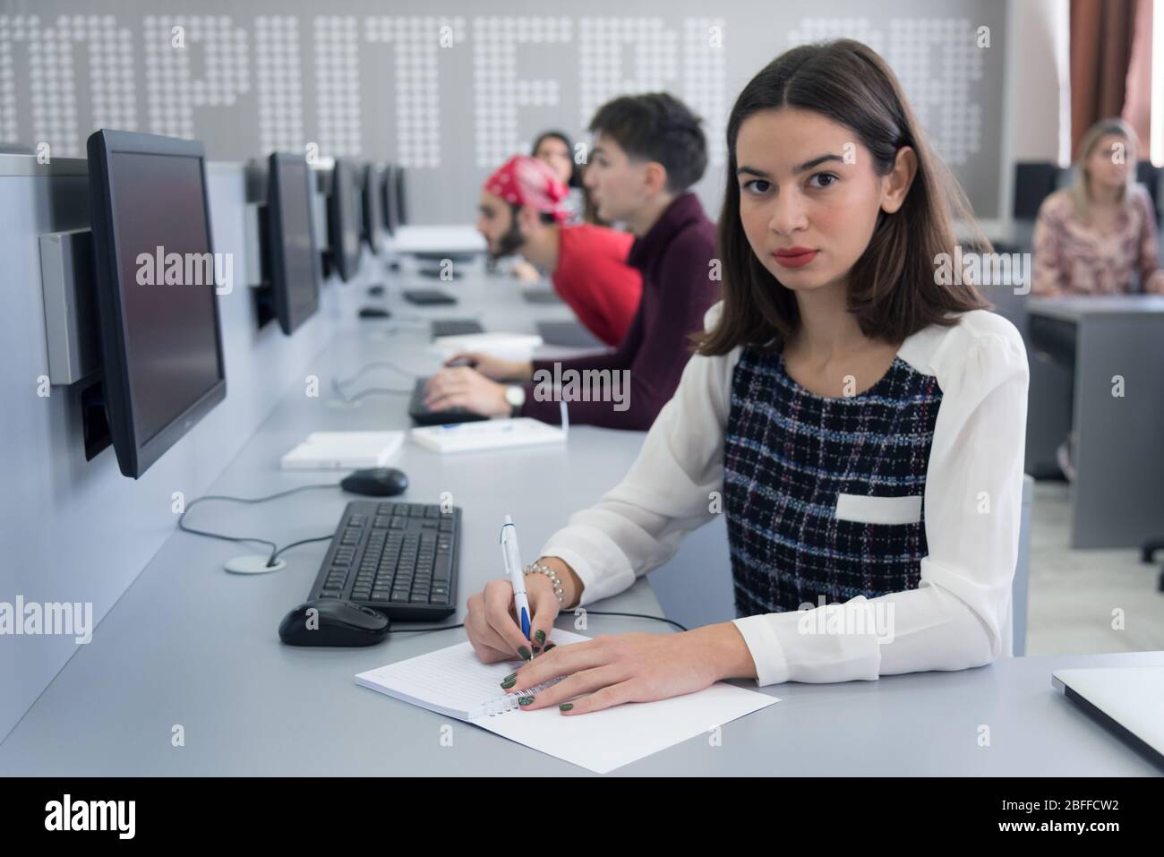 Side view of students using computer in lab. IT student looking and ...