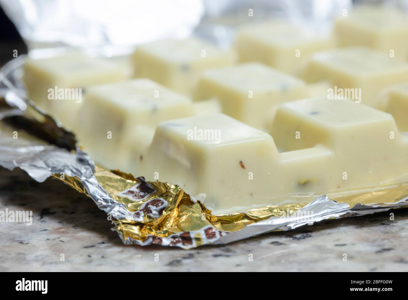 White chocolate block close-up. The package has an opened aluminum foil ...