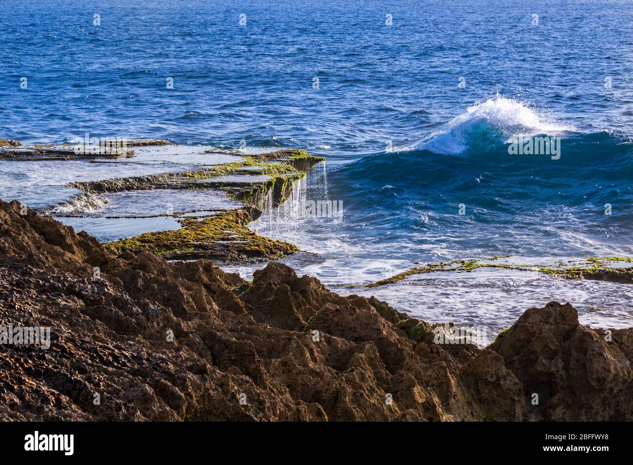 Tidepool on overhanging ledge, water cascading back into the sea, Devil ...