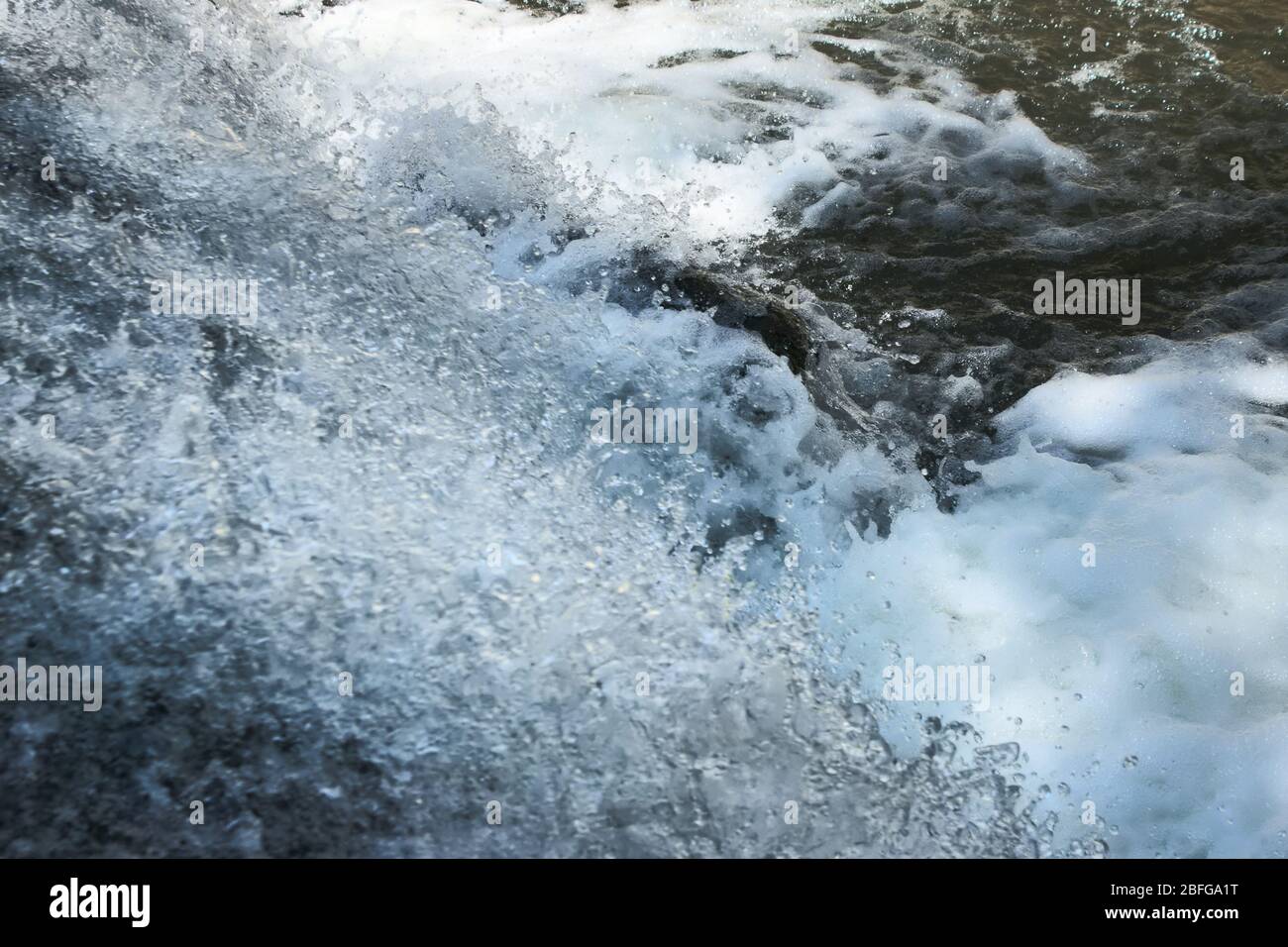 Clear, fresh stream of water splattering in a natural creek ...