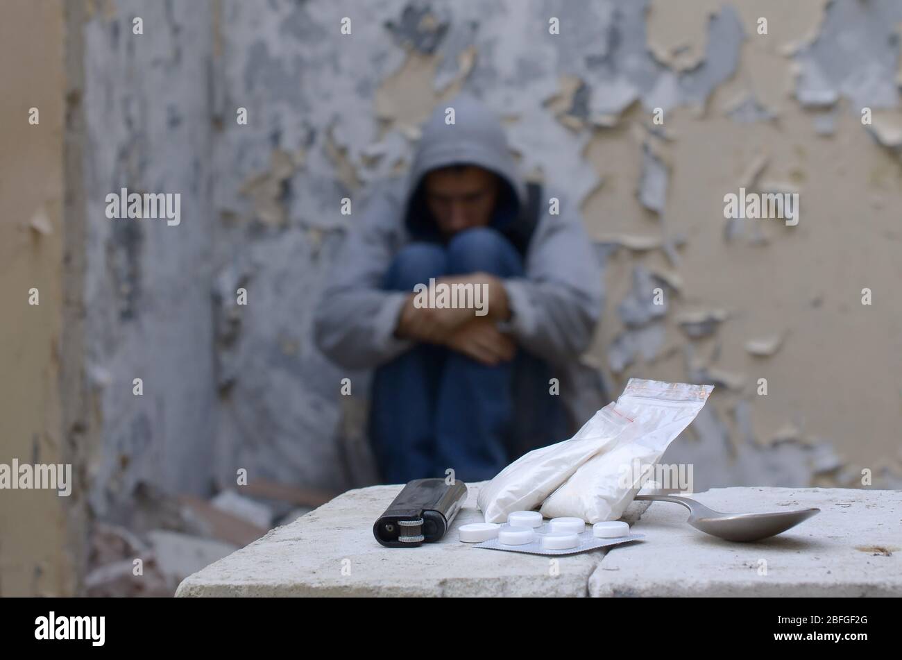 Young man in despair suffers from narcotic effects next to packs of ...