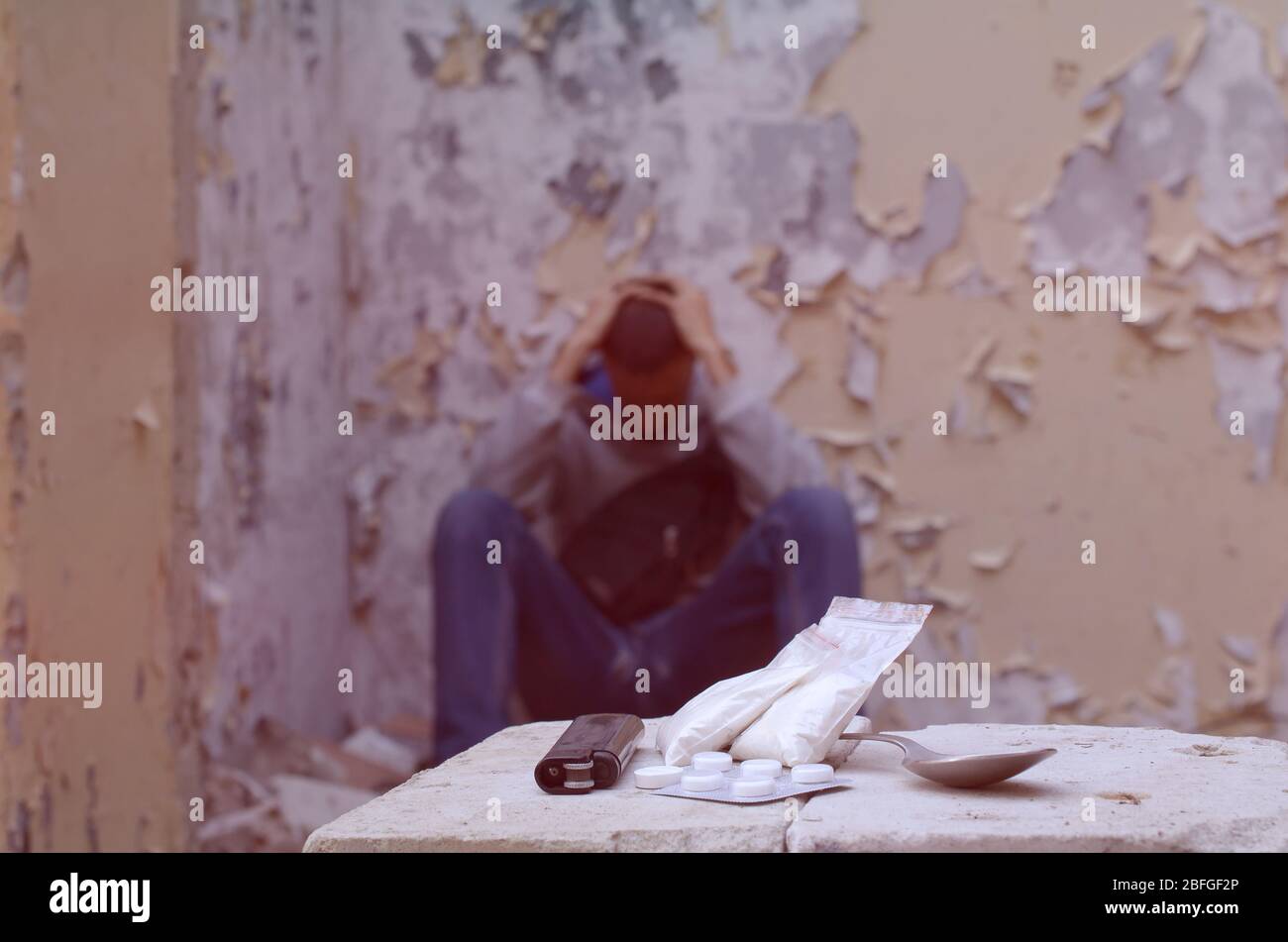 Young man in despair suffers from narcotic effects next to packs of ...