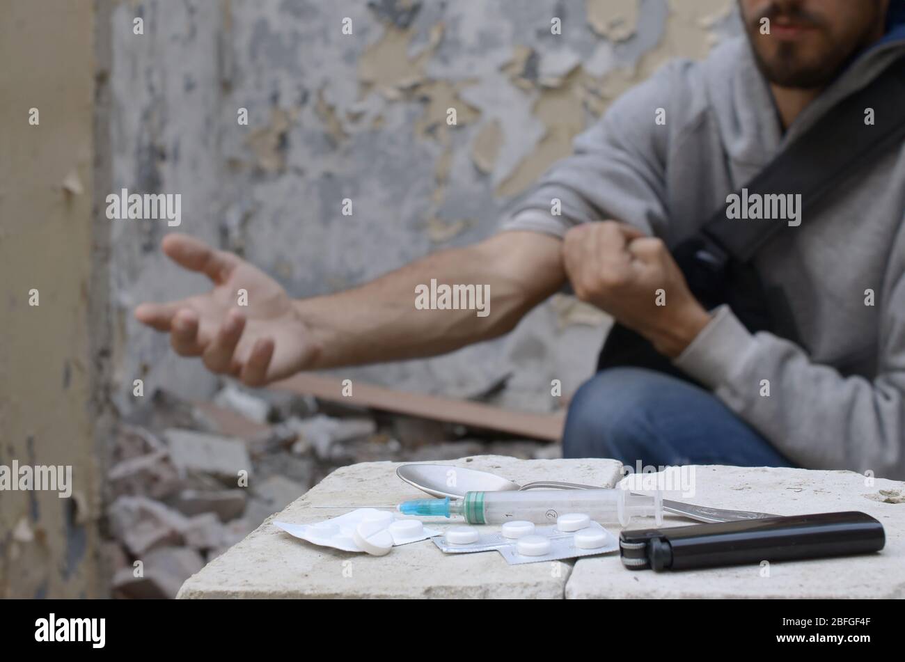 Addict prepares veins on his hands for drug injection next to few pills ...