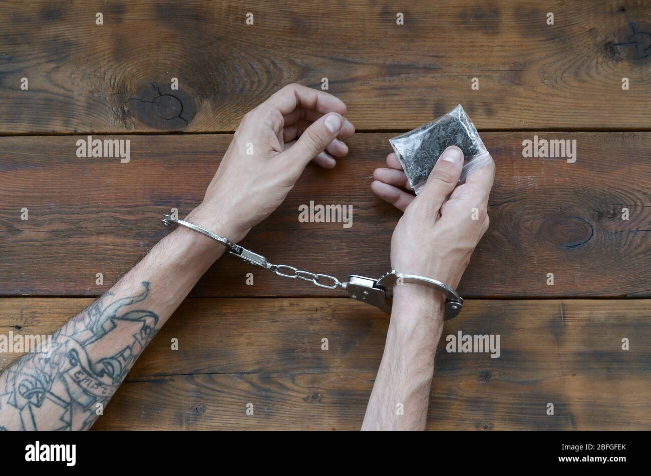 Arrested drug dealer hands in police handcuffs with small hash drug ...