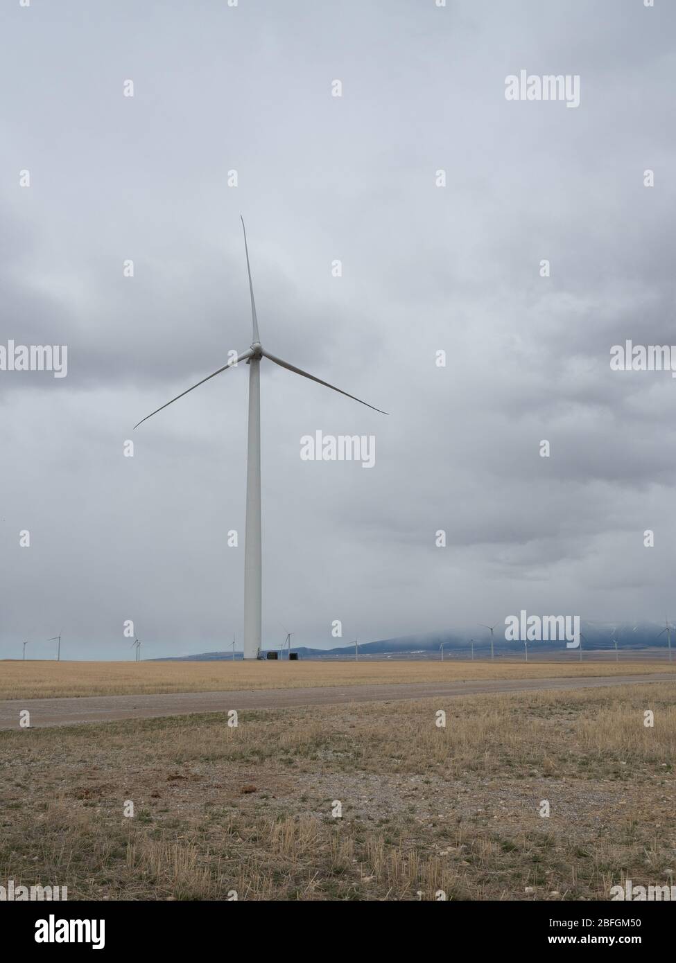 Close up of a wind turbine in a wind farm with gray clouds above the ...