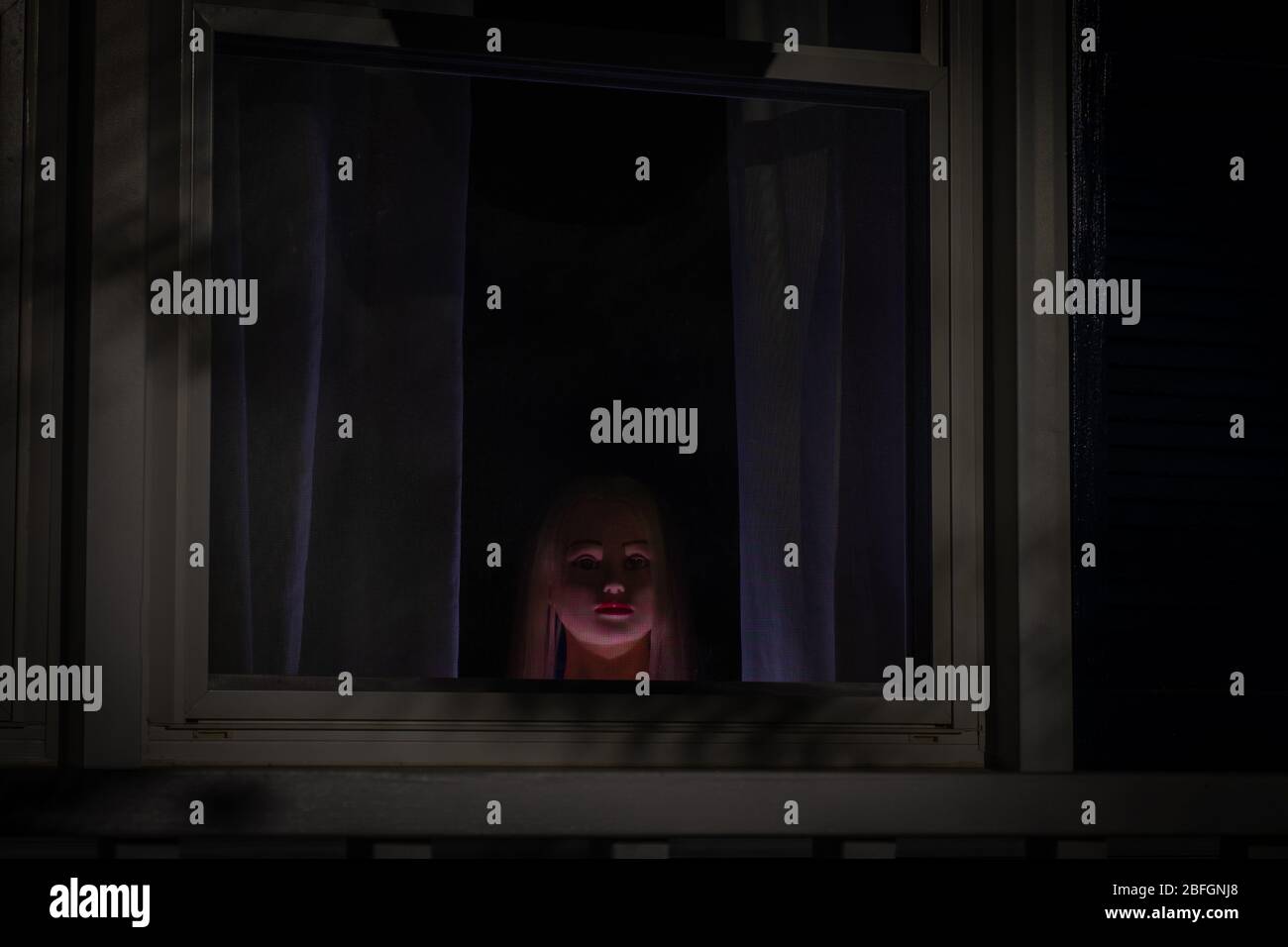A mannequin head looks like a real little girl peering out a screened ...