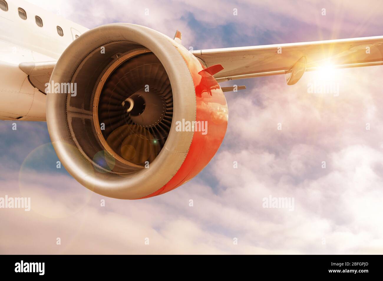 Airplane with red engine in flight through sunset or sunrise clouds ...