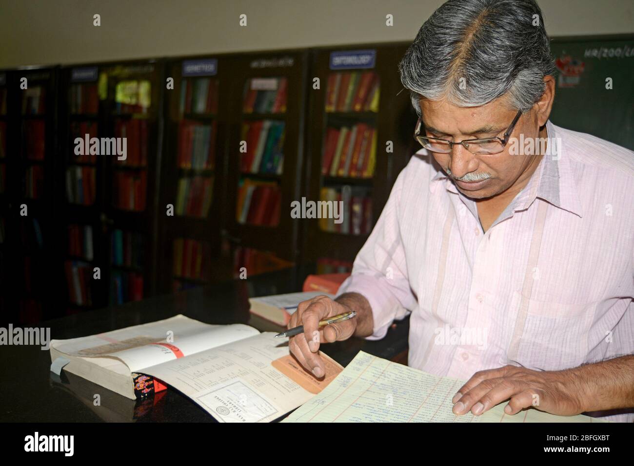 Male Librarian managing the book card in library Stock Photo - Alamy