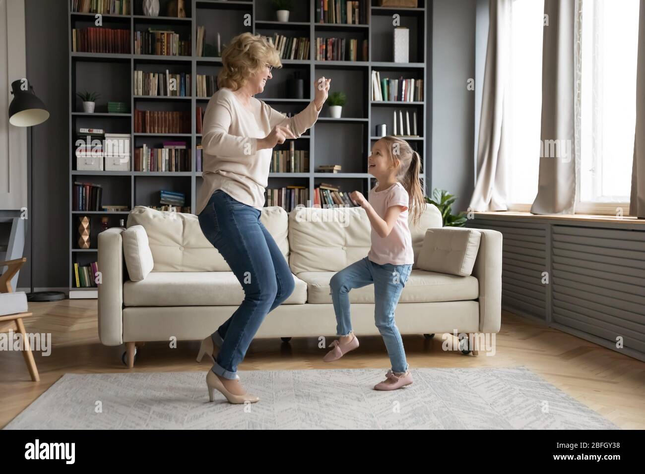 Lively aged grandmother dancing with little granddaughter at home Stock ...