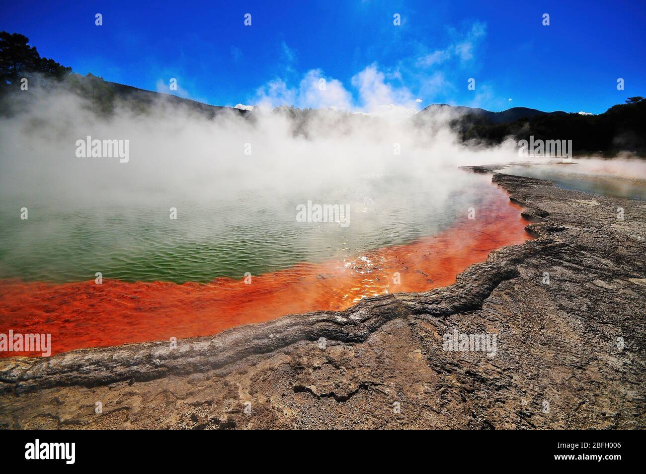 Hot water pool with orange rocks underwater steam and blue sky Stock ...