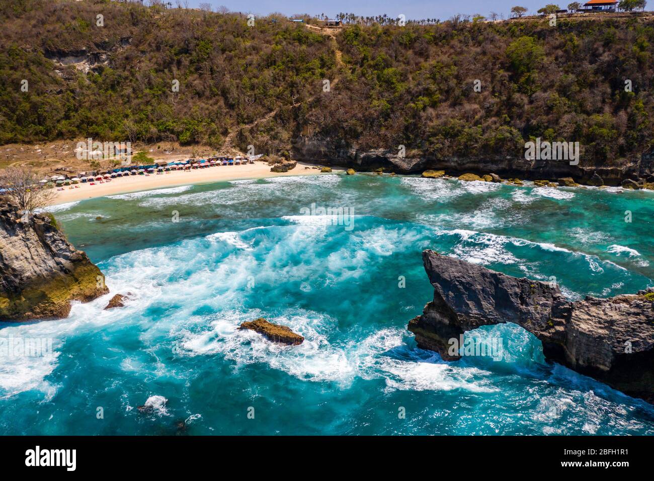 Aerial view of huge ocean waves, an offshore rocky archway and tropical ...
