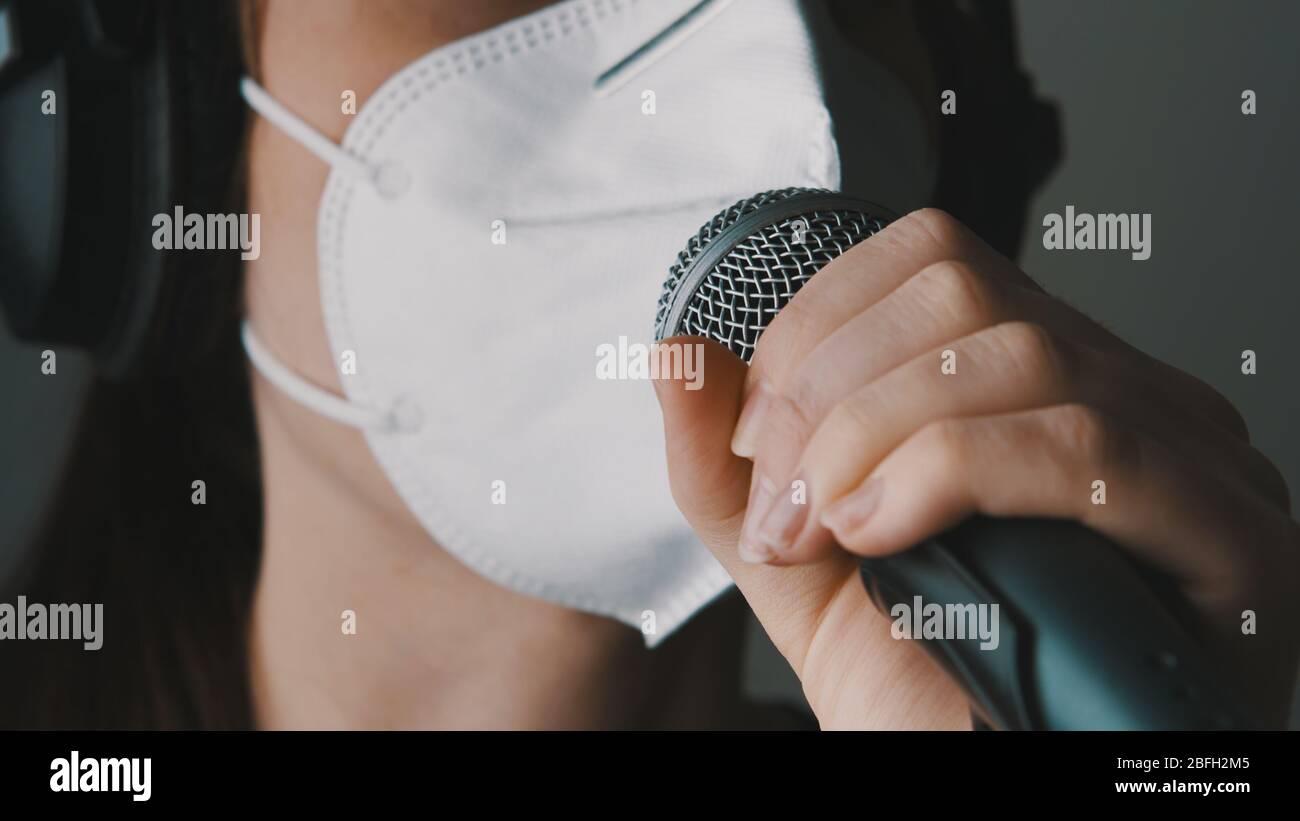 Young singer singing in the microphone fith face mask in home studio ...