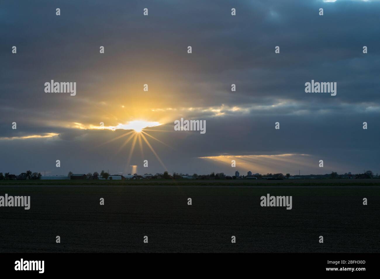 Sun peeks through the clouds. Beautiful sun beams or crepuscular rays ...