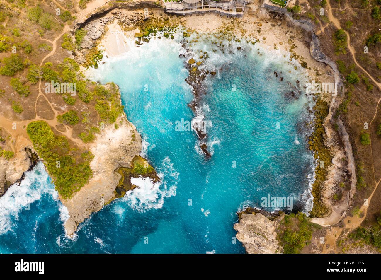 Top down aerial view of waves breaking inside a small rocky bay (Blue ...