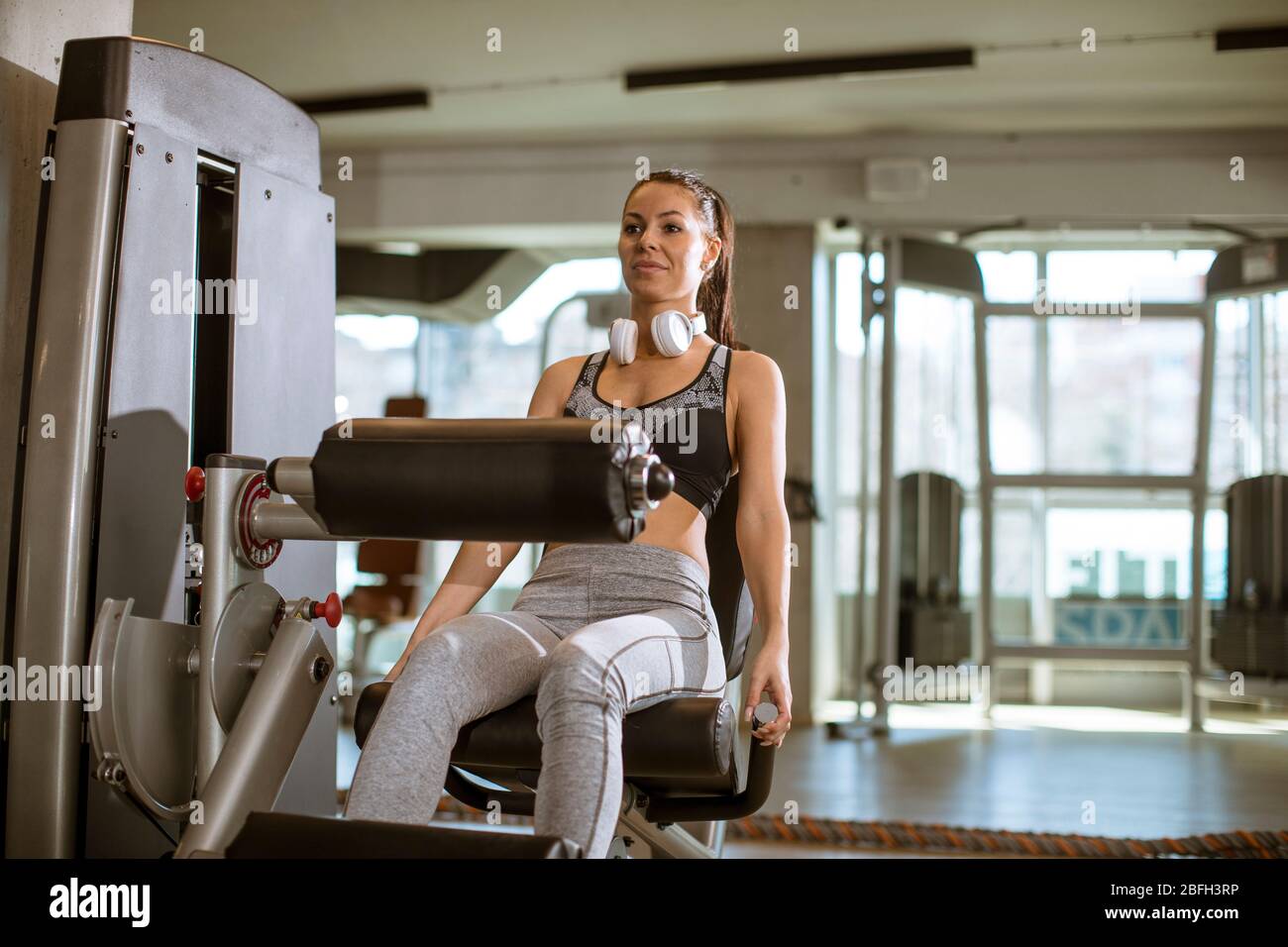 Pretty young woman having exercises on leg extension and leg curl ...