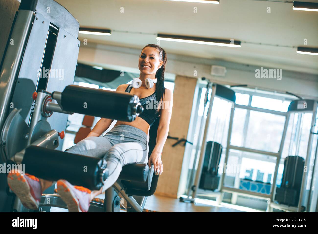 Pretty young woman having exercises on leg extension and leg curl ...
