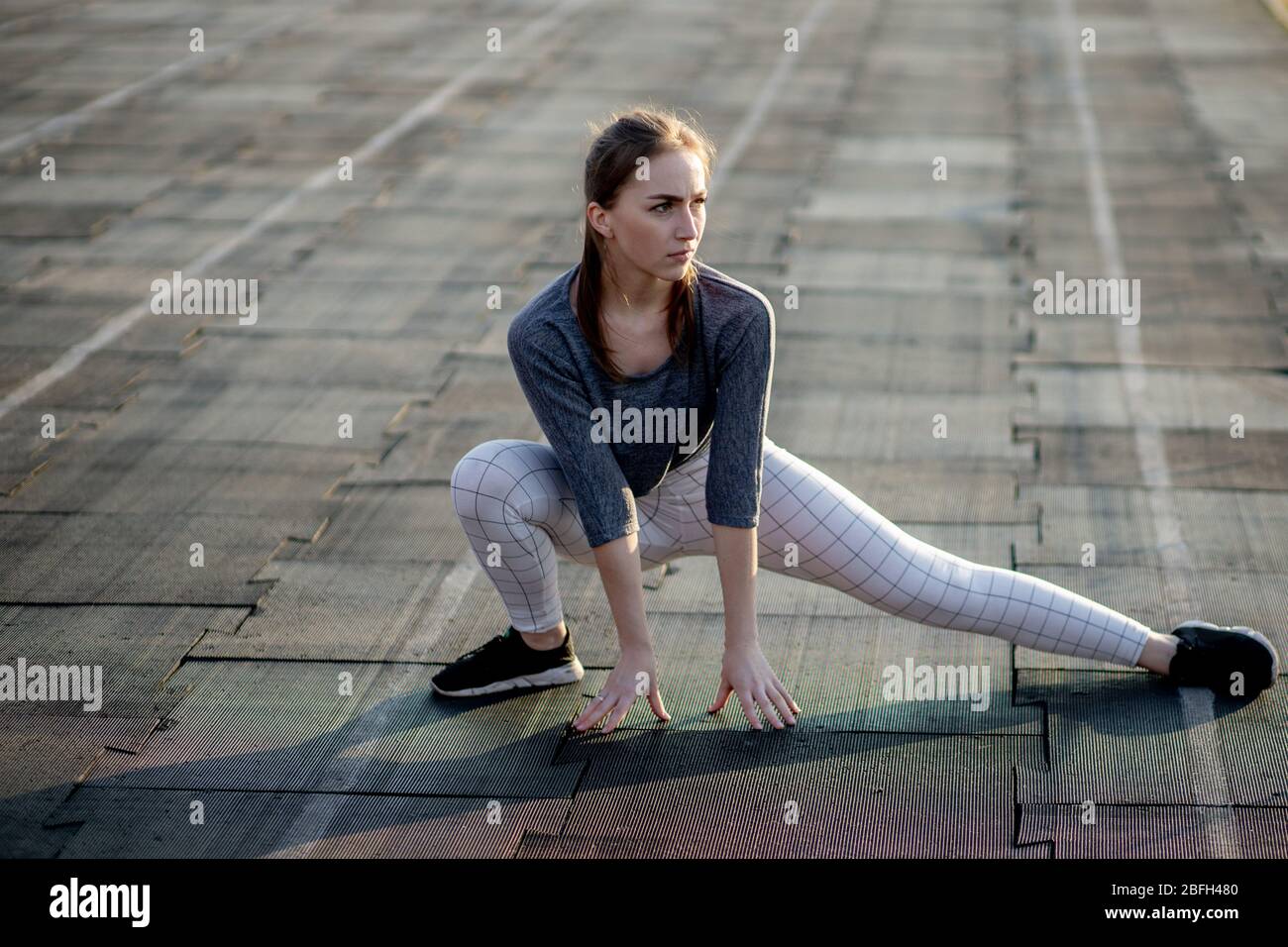 Female runner stretching legs on running track Stock Photo - Alamy