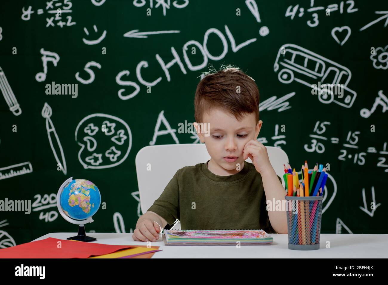 Cute child boy doing homework. Clever kid drawing at desk. Schoolboy ...