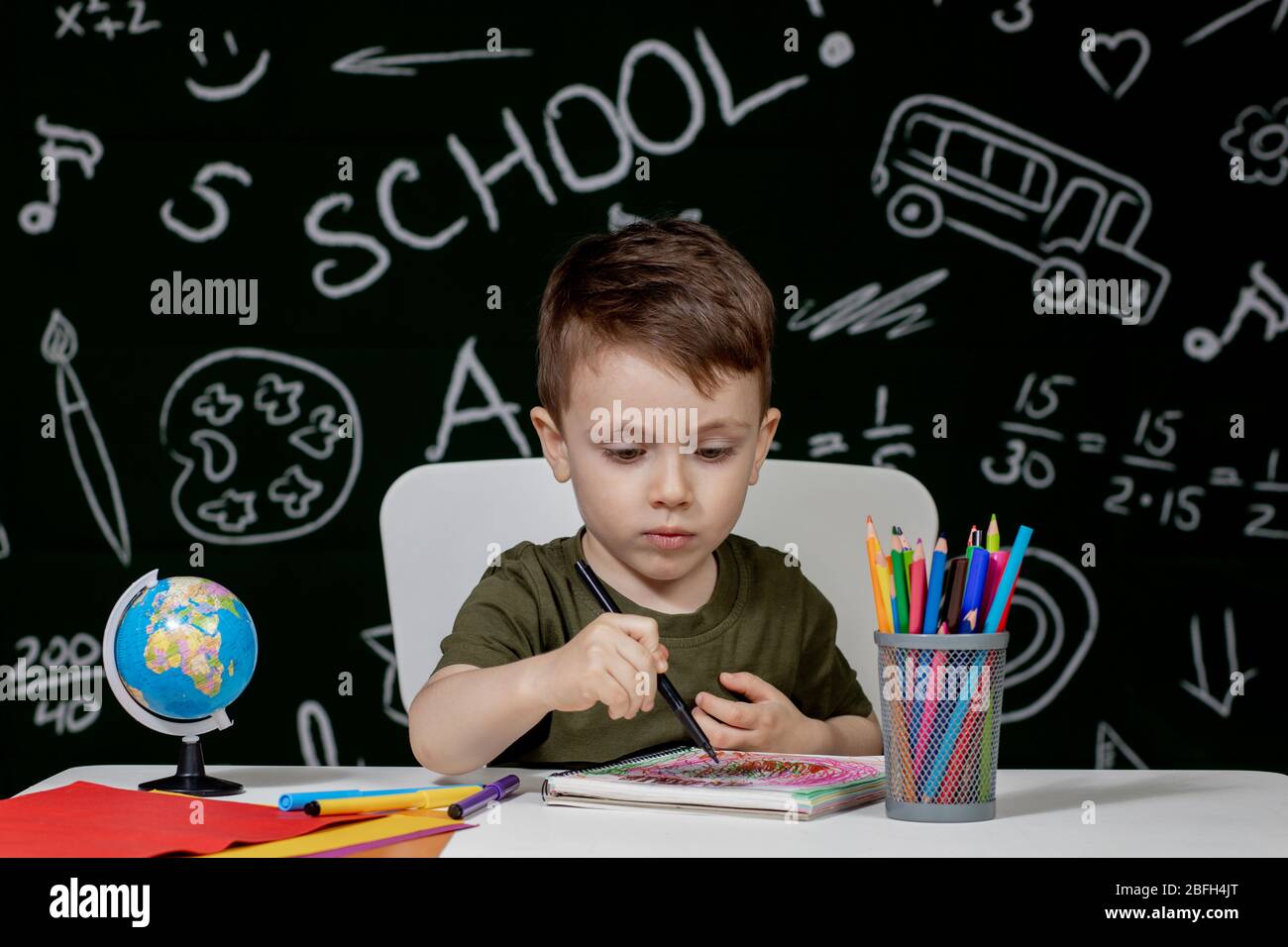 Cute child boy doing homework. Clever kid drawing at desk. Schoolboy ...