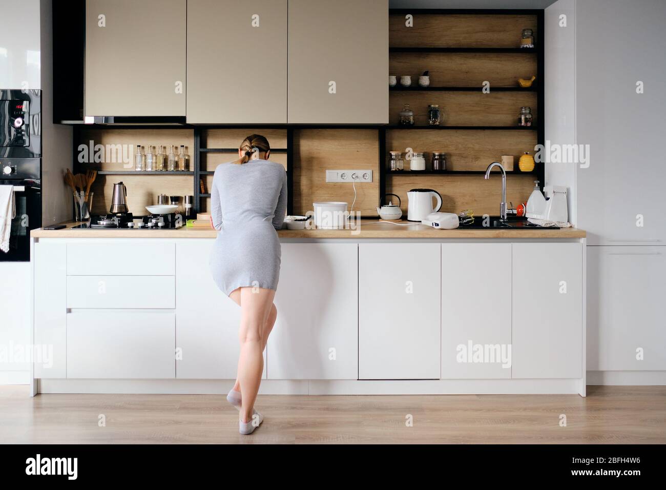 Young woman with beautiful body standing next to a modern kitchen while ...