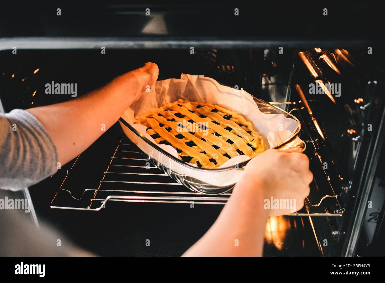 Attractive awesome girl putting baking sheet pie in oven while day ...