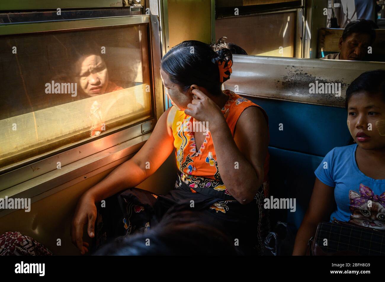 Burmese woman looking at her reflection on the Circle Line, Yangon ...