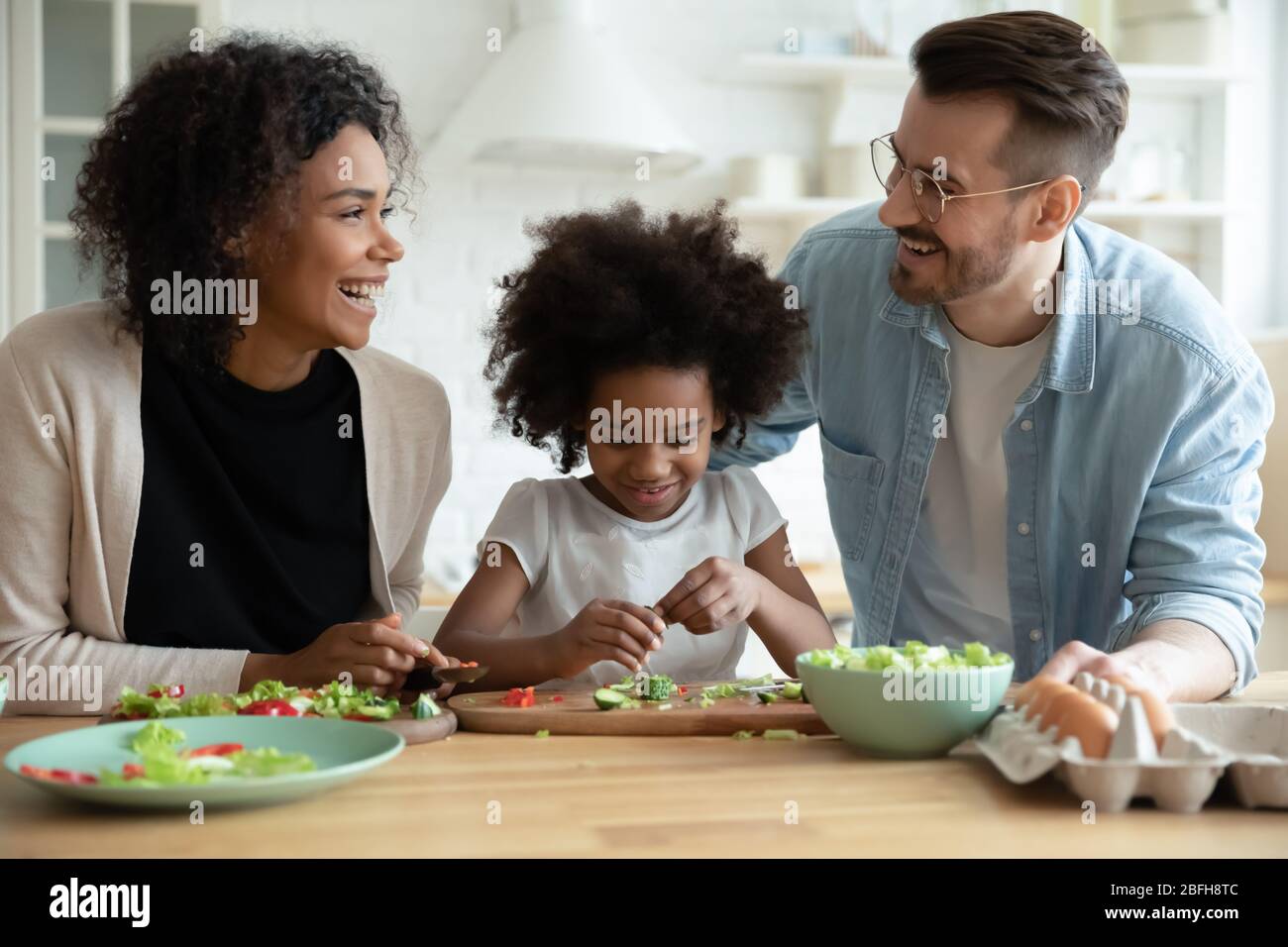 Young multiracial family with kid cooking in kitchen together Stock ...