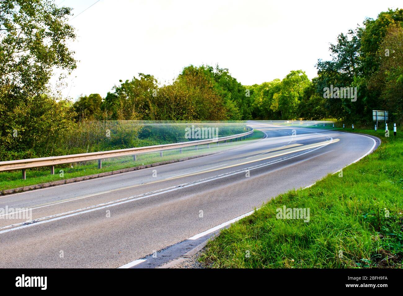 Slow shutter speed for motion blur of car on country road in daytime ...
