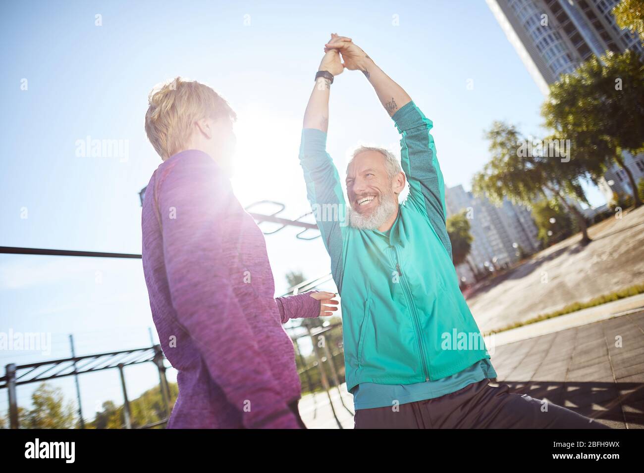Morning exercises. Happy mature family couple in sportswear warming up ...
