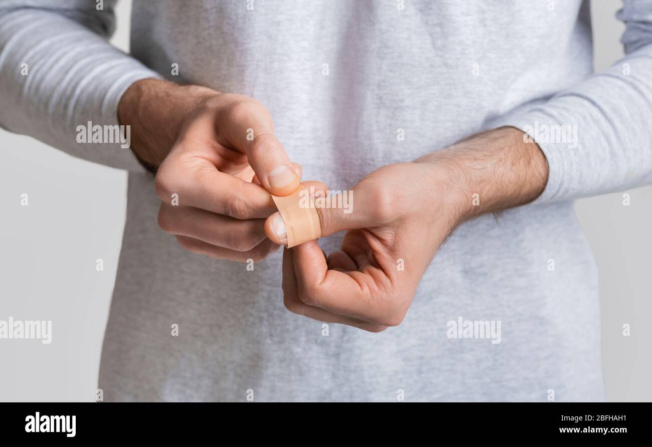 Man wrapping wound on finger with band-aid Stock Photo - Alamy