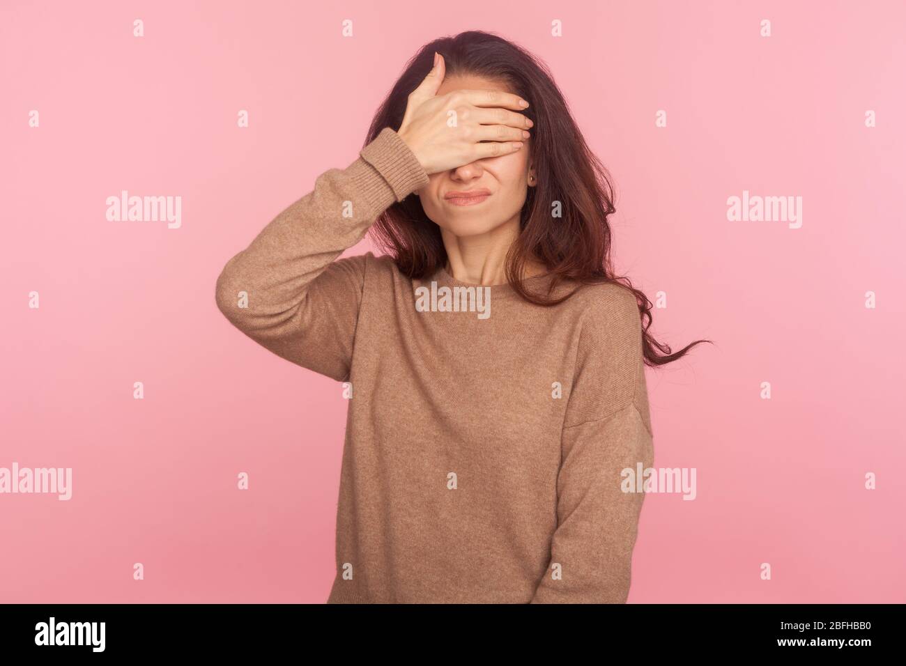 Don't want to look! Portrait of young woman hiding her displeased face ...