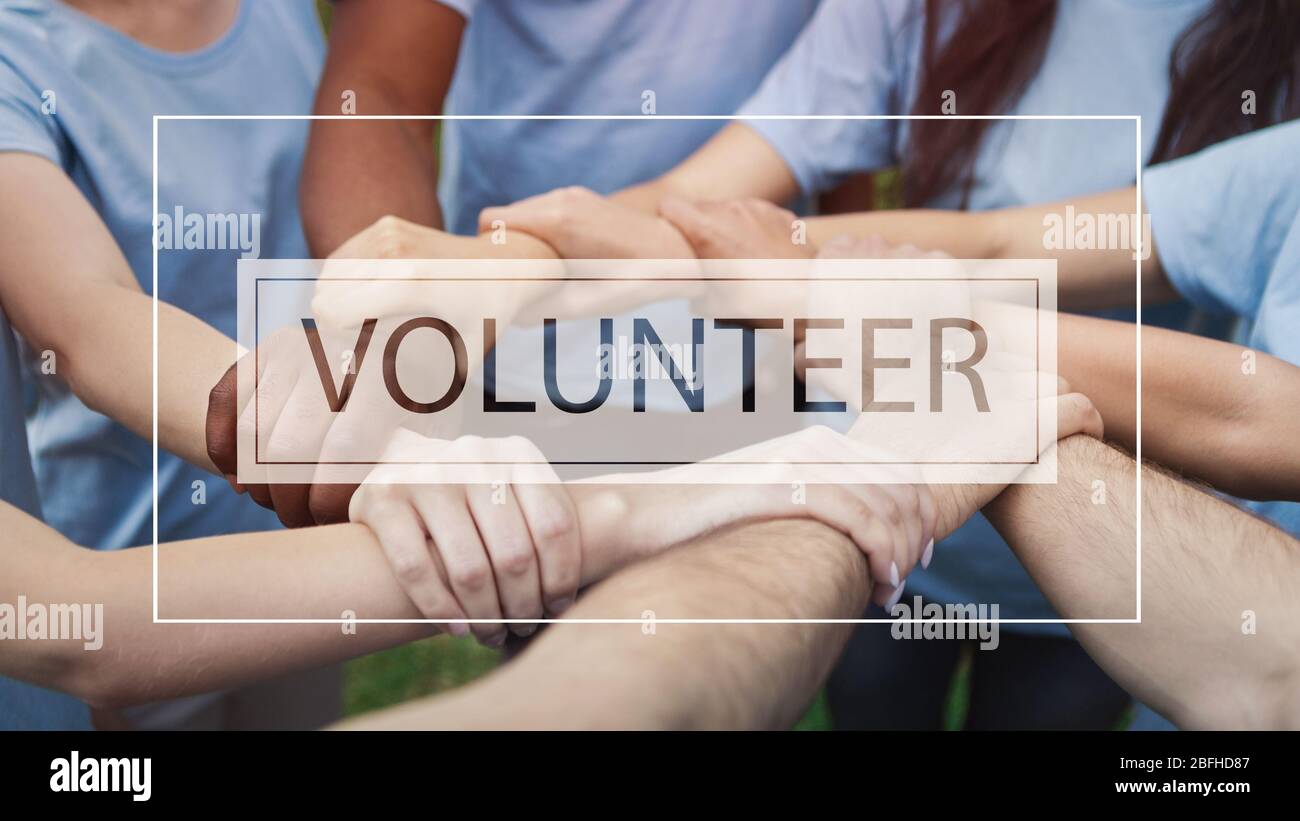 Ecological unity. Millennial people holding hands and word VOLUNTEER ...