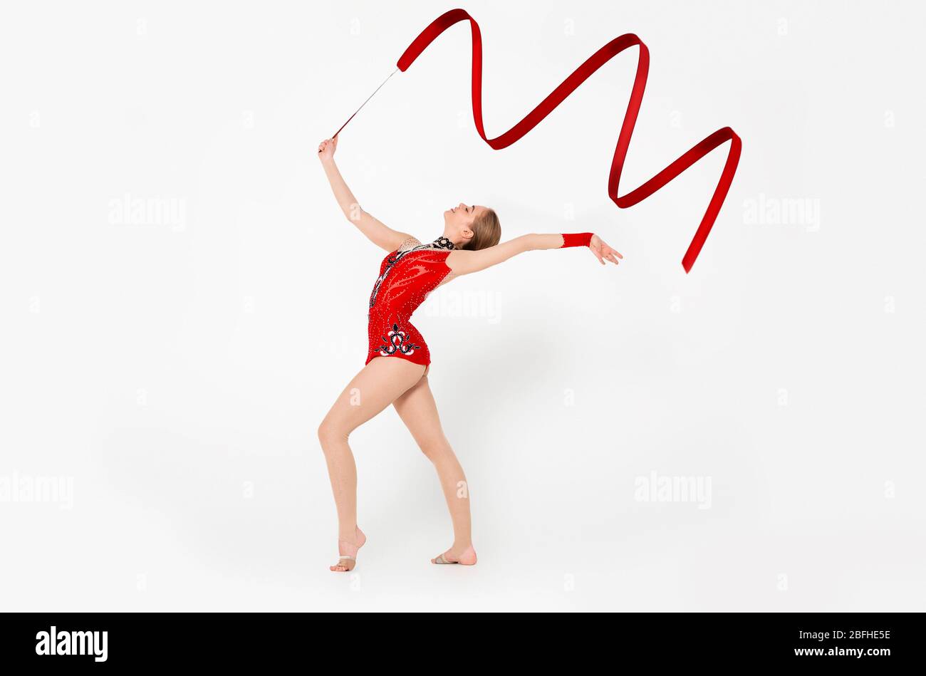 Full length portrait of charming gymnast dancing with ribbon on white ...