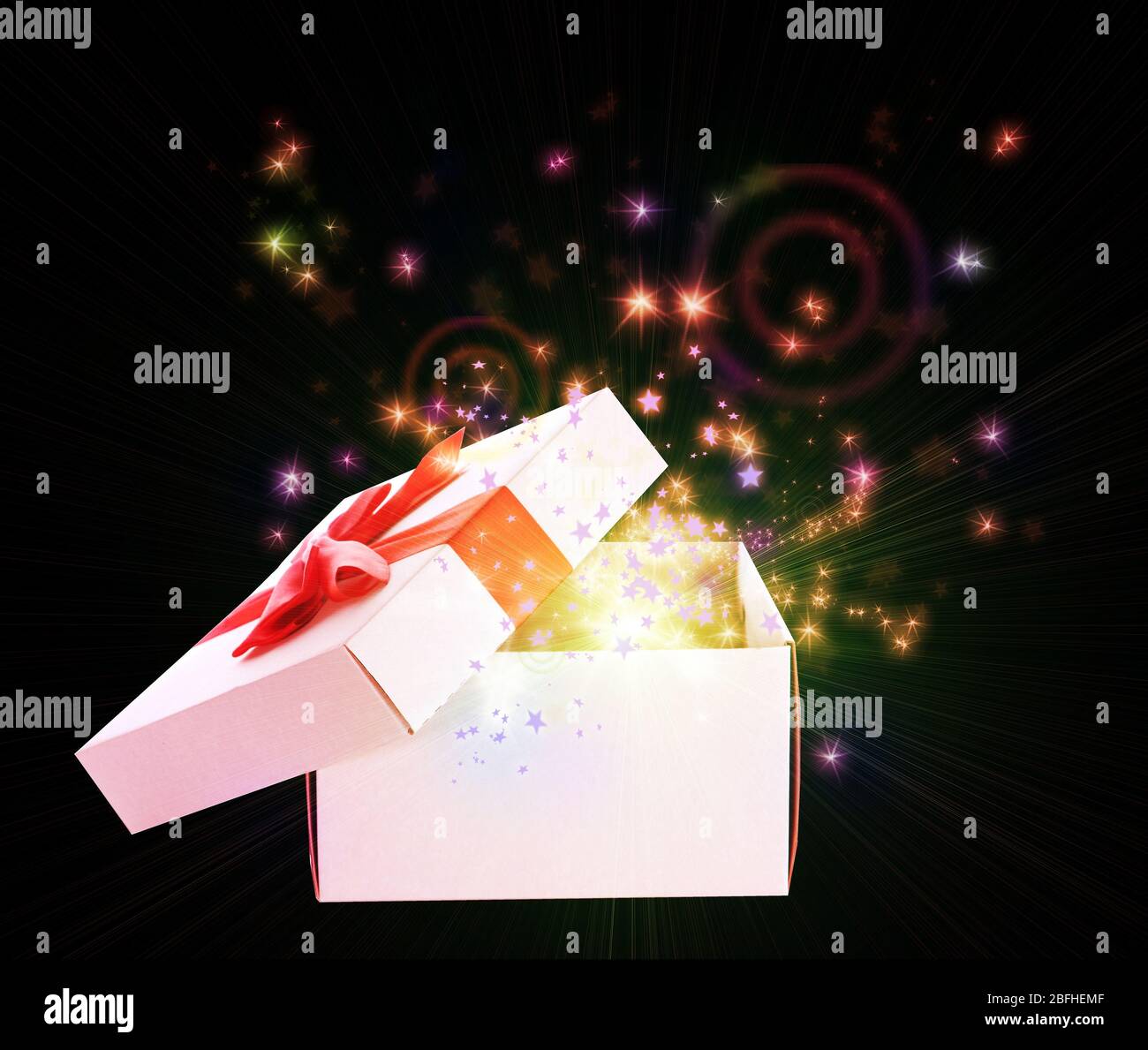 Gift box with red ribbon with sparkles on black background Stock Photo ...