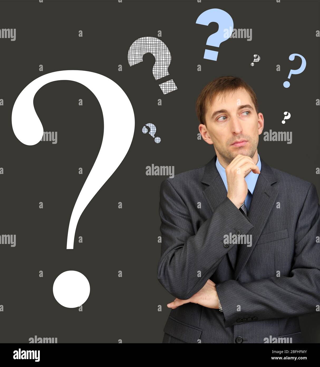 Man thinking surrounded by question on dark background Stock Photo - Alamy