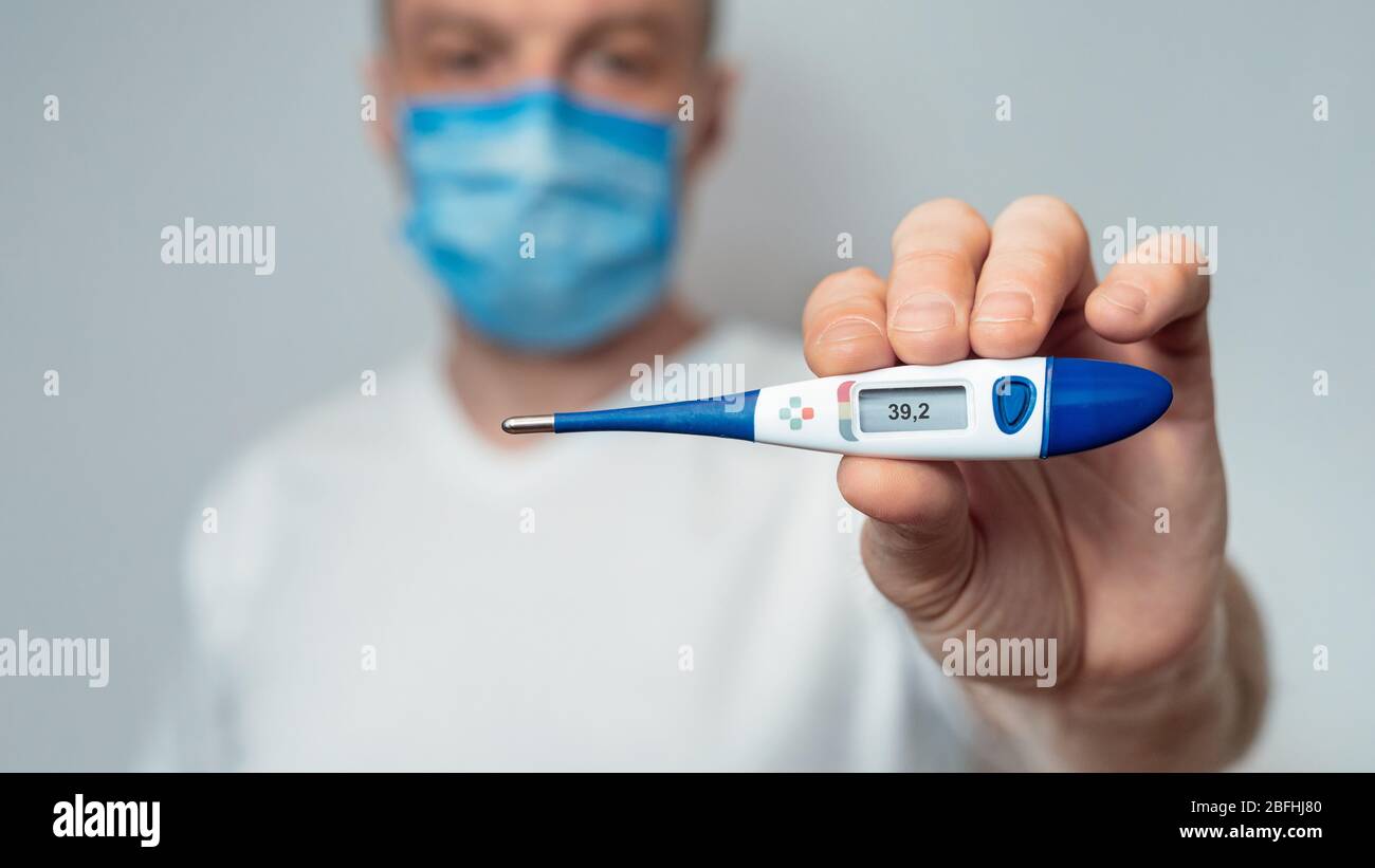 Man Having Fever Showing Thermometer Over Gray Background, Wearing Mask ...
