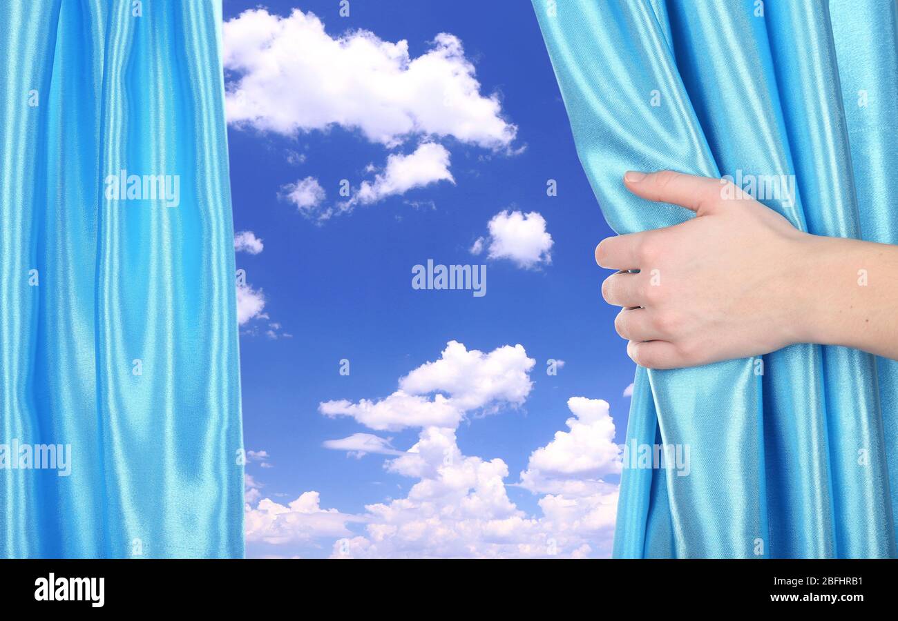 Hand opening curtain on sky background Stock Photo - Alamy