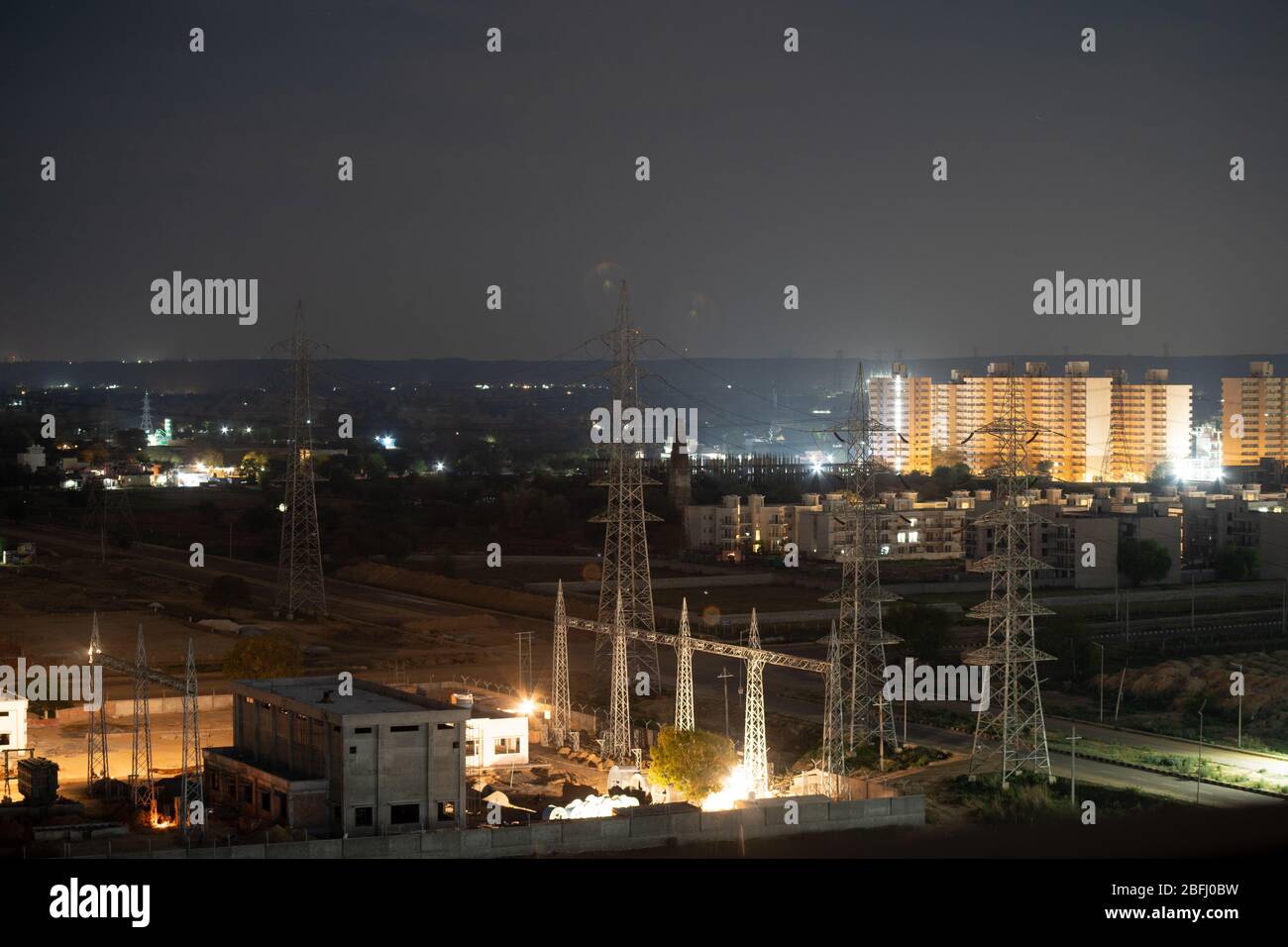 Aerial night shot of a power transformer plant with residential or ...