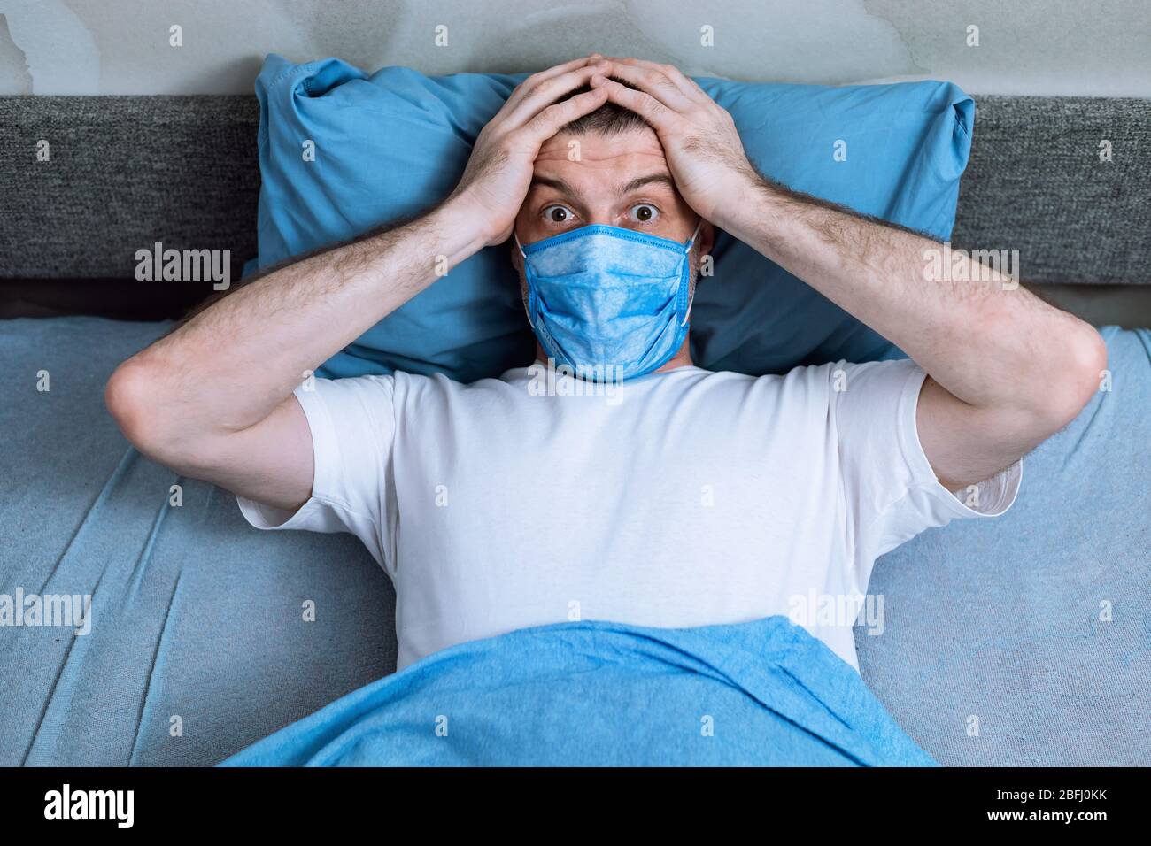 Scared Man Cupping Head In Fear Lying In Bed Indoors Stock Photo - Alamy